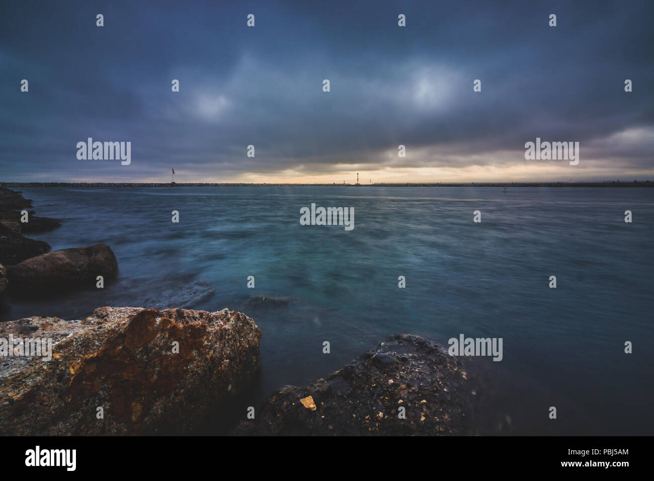 Dramatic clouds and colorful sky at sunset with calm waves along the ...