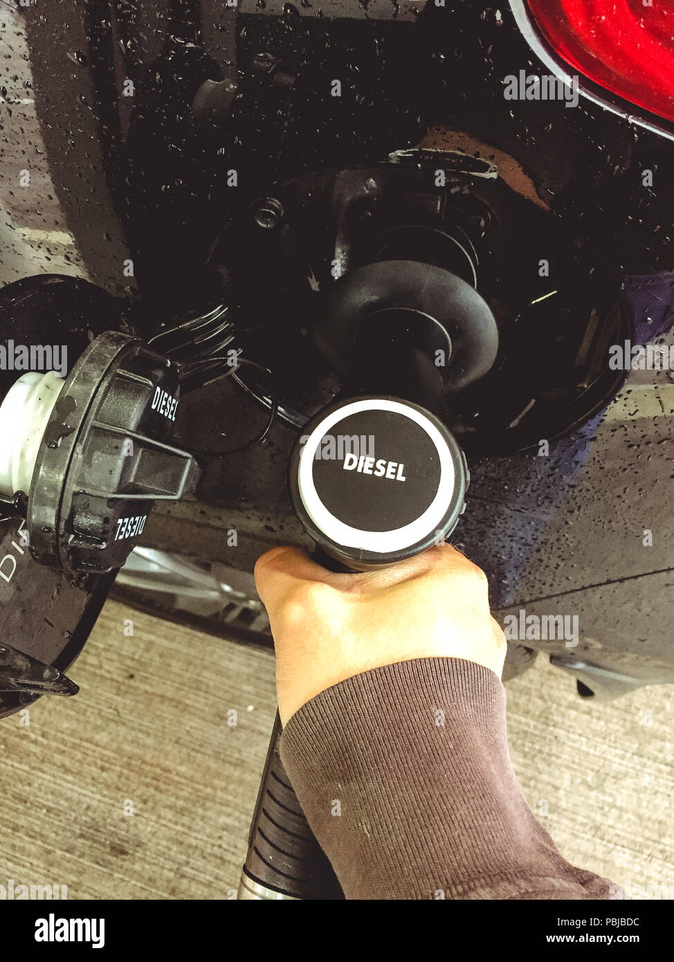 Close up of a hand holding a fuel nozzle and filling up a car with ...