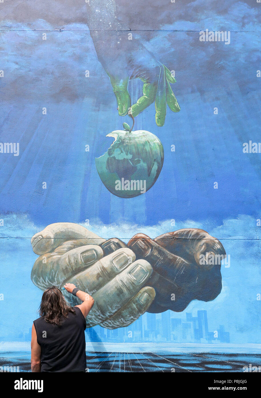 An artist adds the finishing touches to his art work on the side of the ...