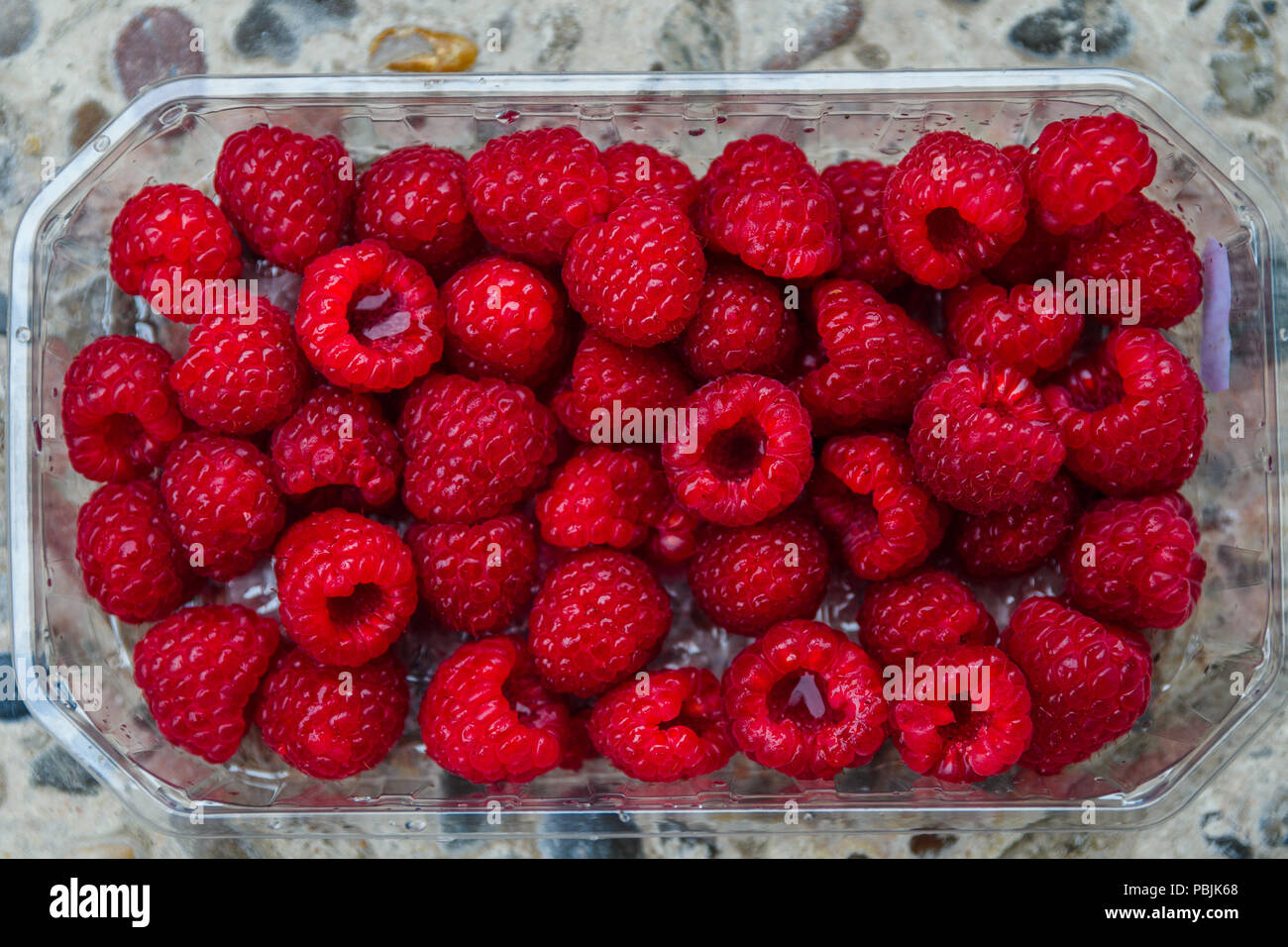Red bright raspberry in plastic box with waterdrops Stock Photo - Alamy