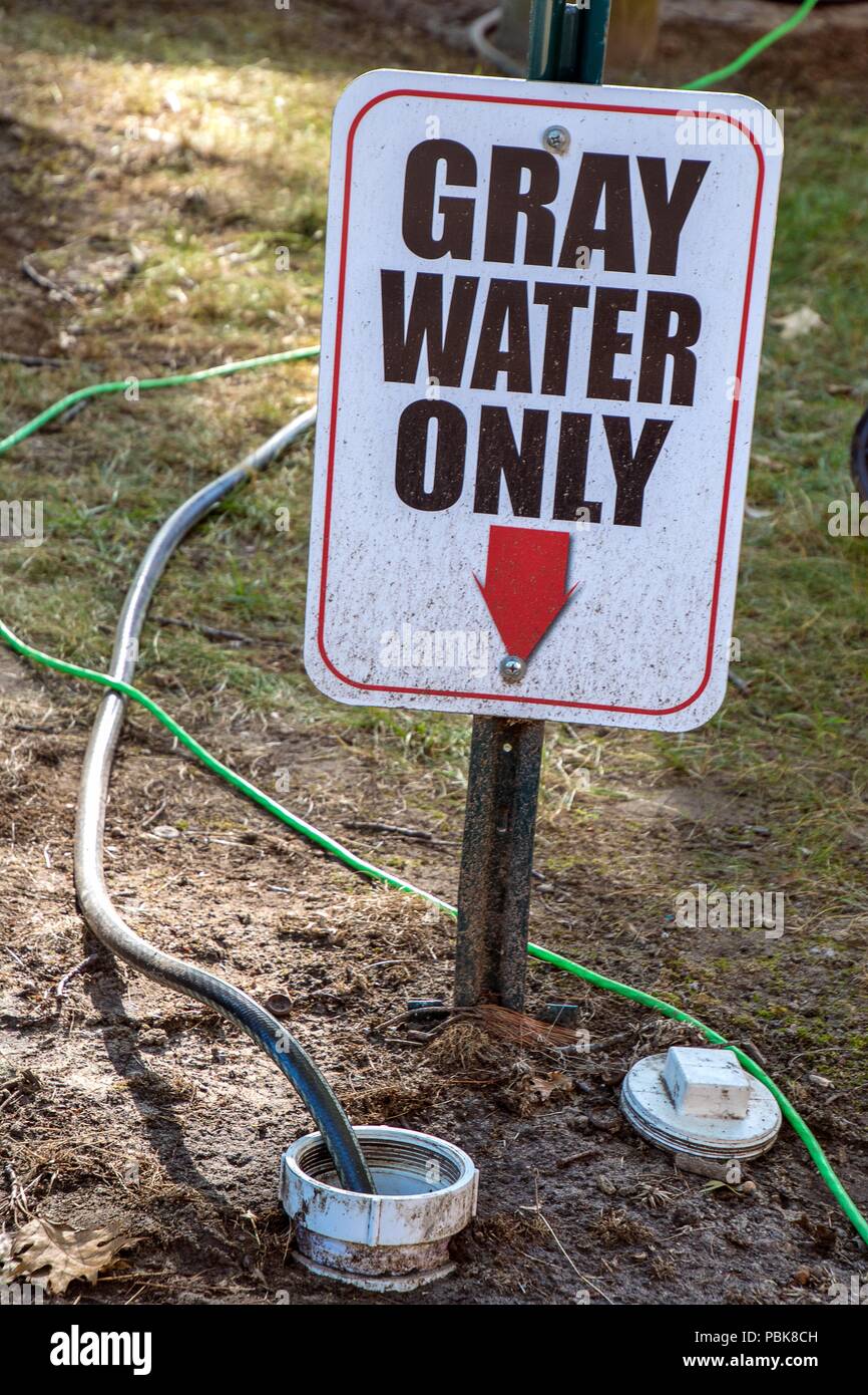 gray water warning sign on metal post in dirt with dirty hoses Stock ...
