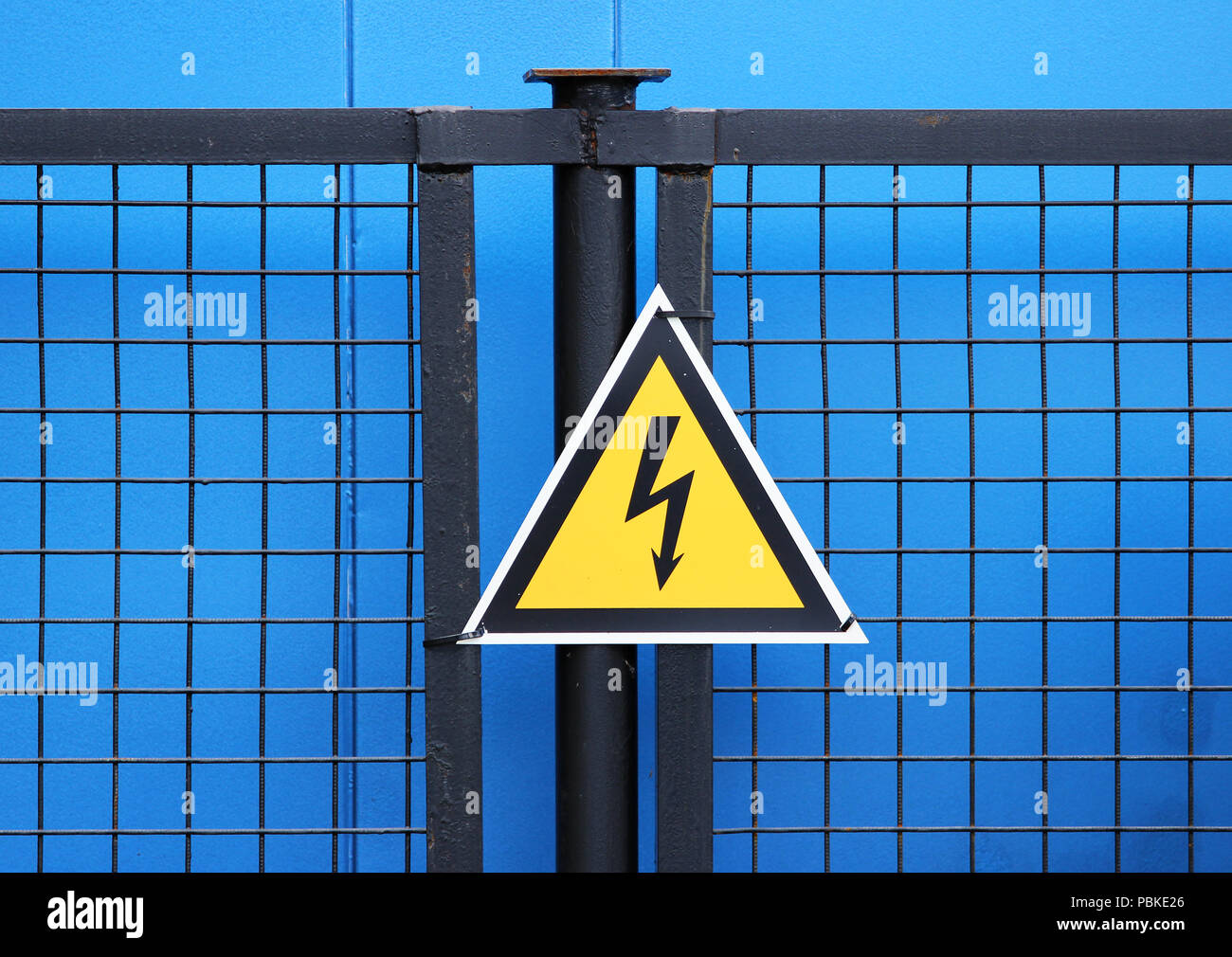 High voltage triangle warning sign mounted on a metal lattice fence on ...