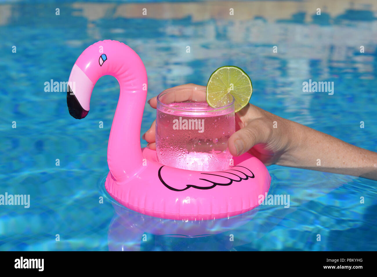 Summer vibes! Woman’s hand, with a cold drink in an inflatable pink ...