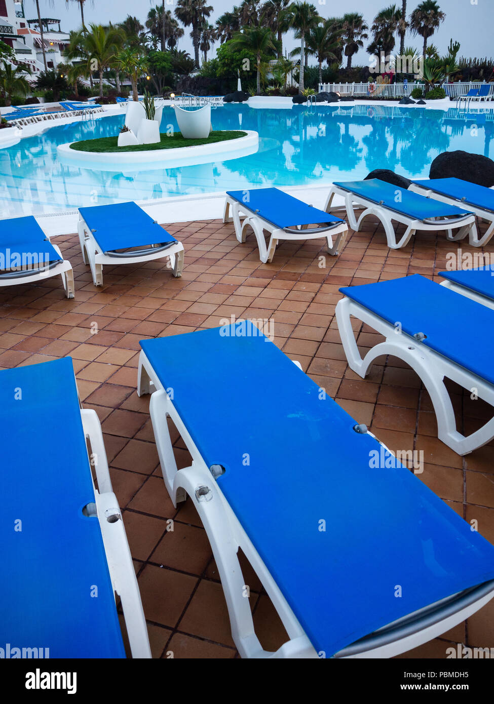 Sun beds by the pool at night / dusk in Tenerife. A row of empty ...