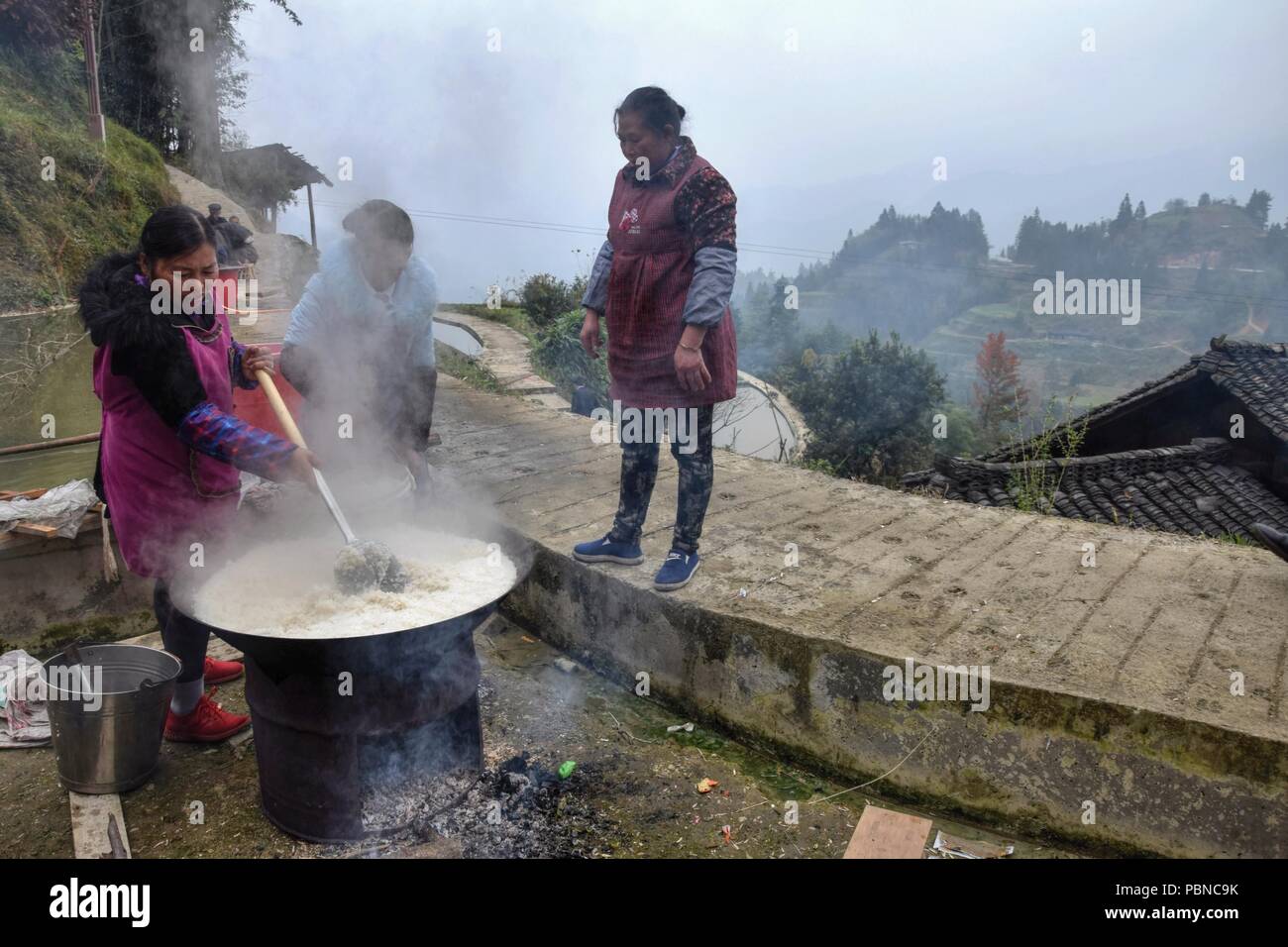 GUIZHOU PROVINCE, CHINA – CIRCA DECEMBER 2017: Three women cook a rice ...