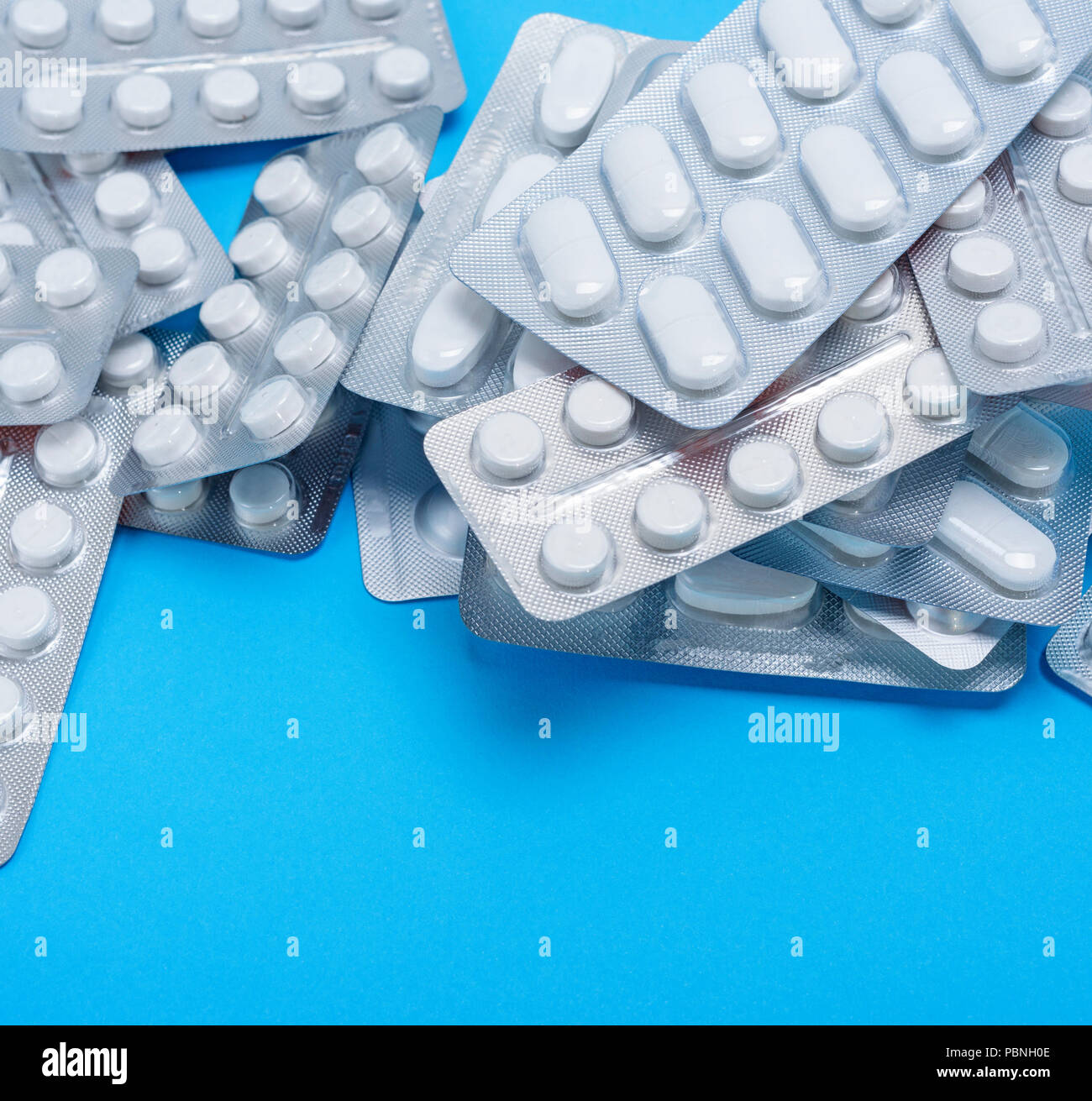 different white tablets in a package are scattered on a blue background ...