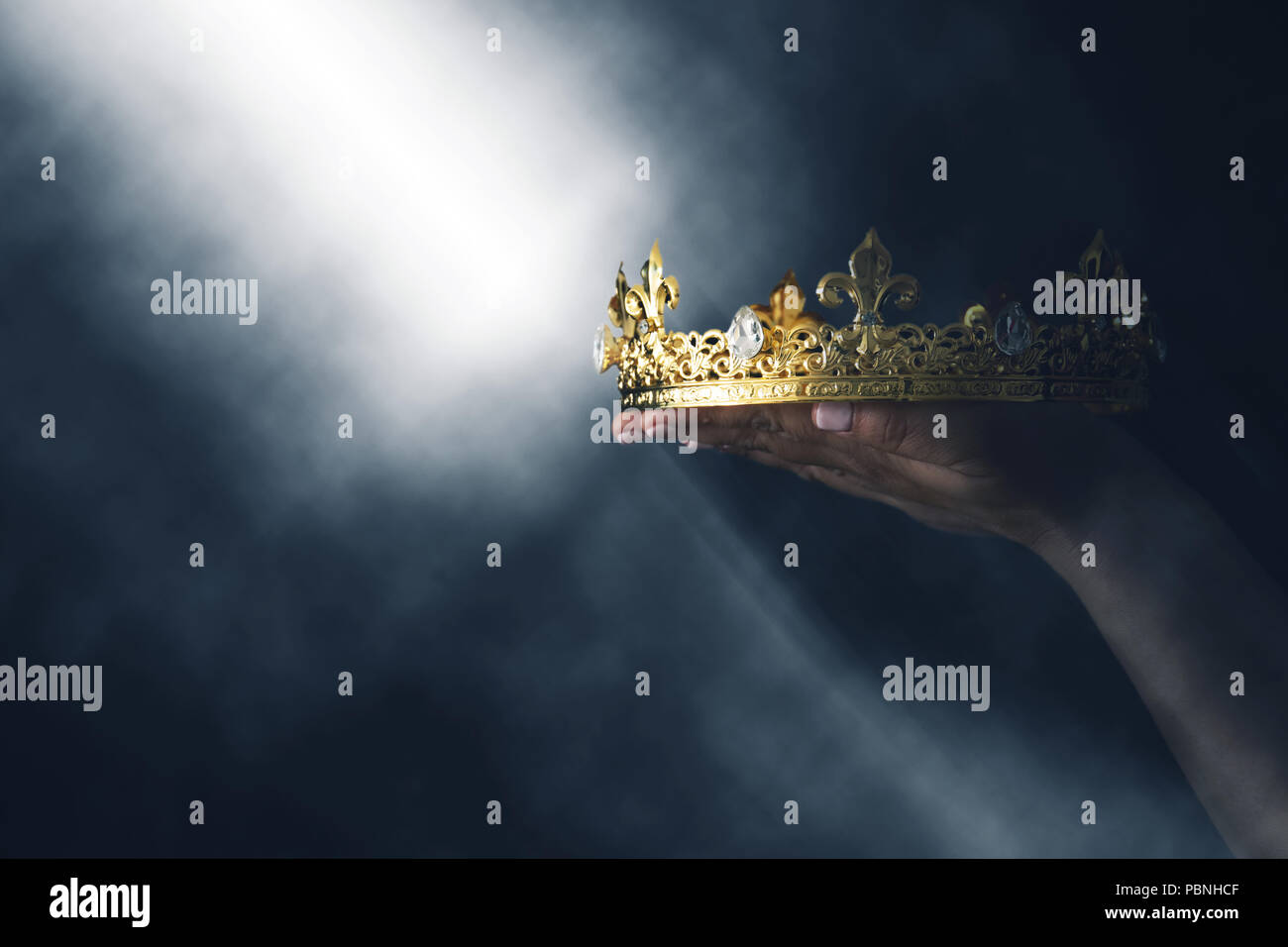 mysteriousand magical image of woman's hand holding a gold crown over ...