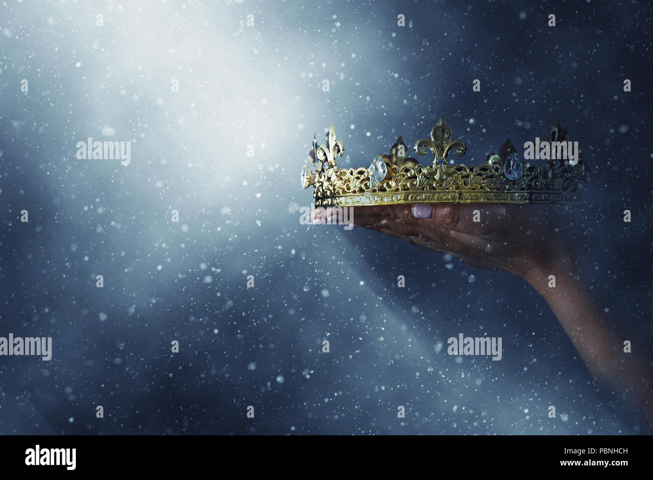 mysteriousand magical image of woman's hand holding a gold crown over ...