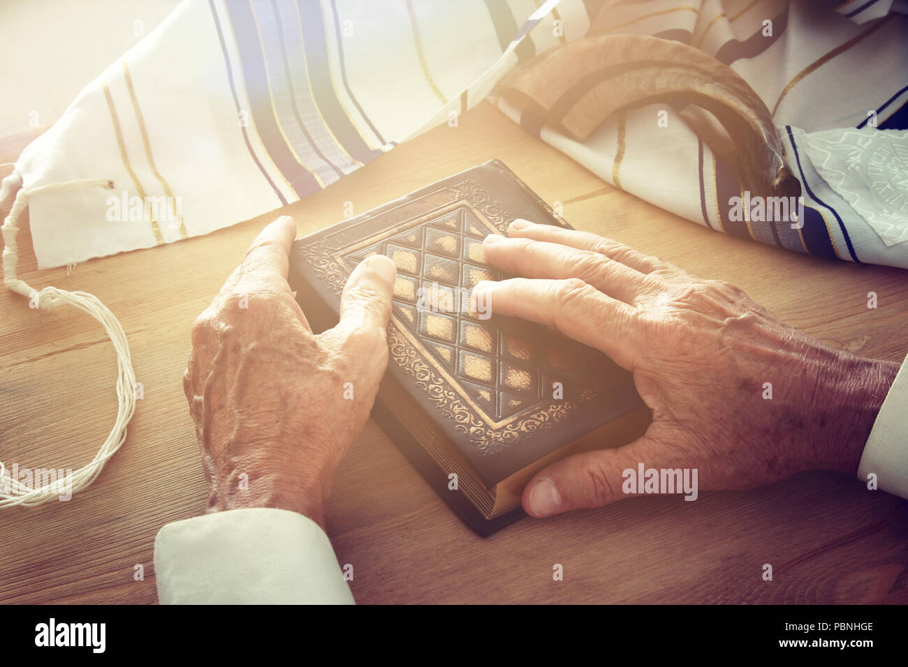 Old Jewish man hands holding a Prayer book, praying, next to tallit and ...
