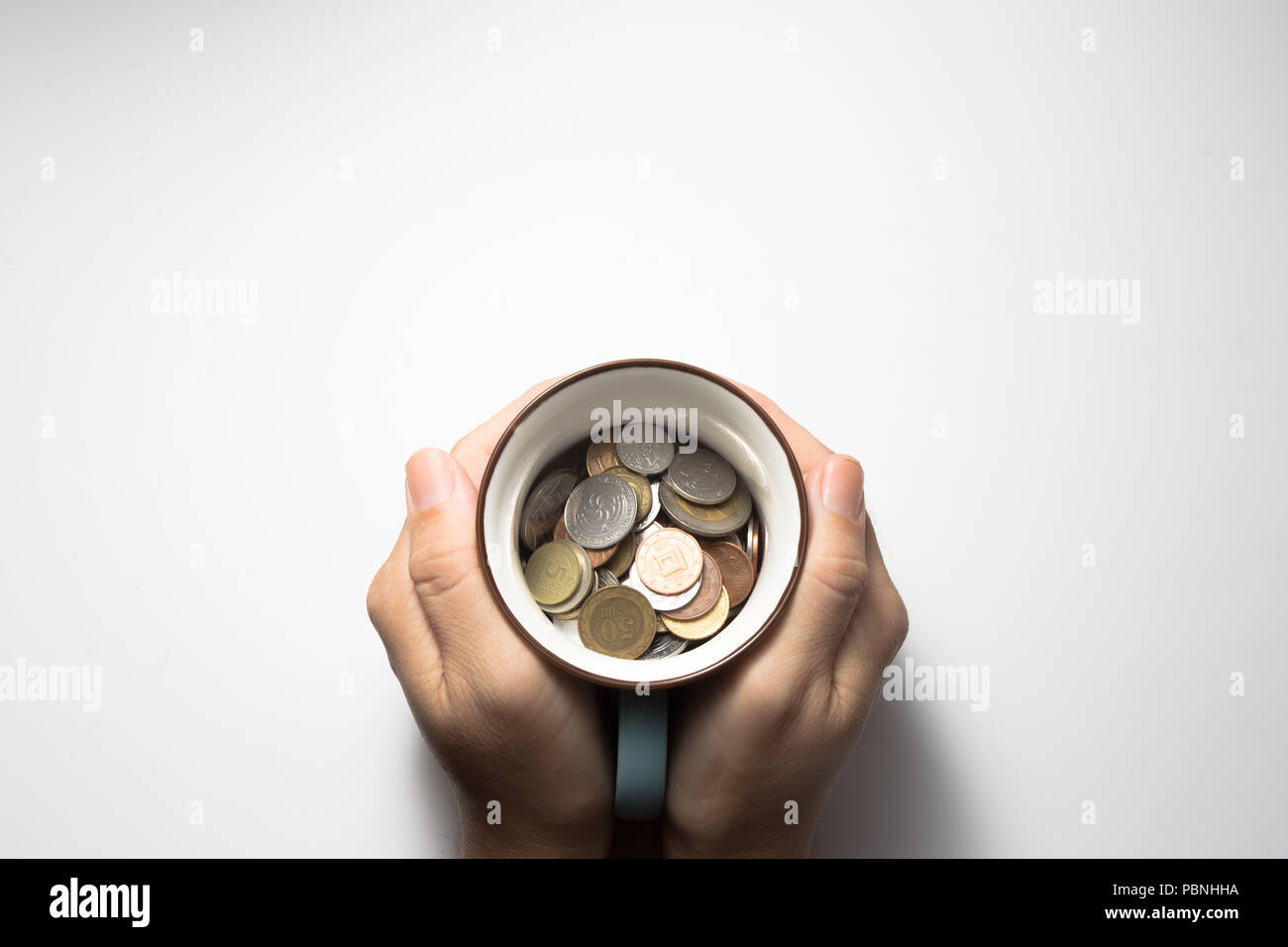 money in a cup on white background Stock Photo - Alamy