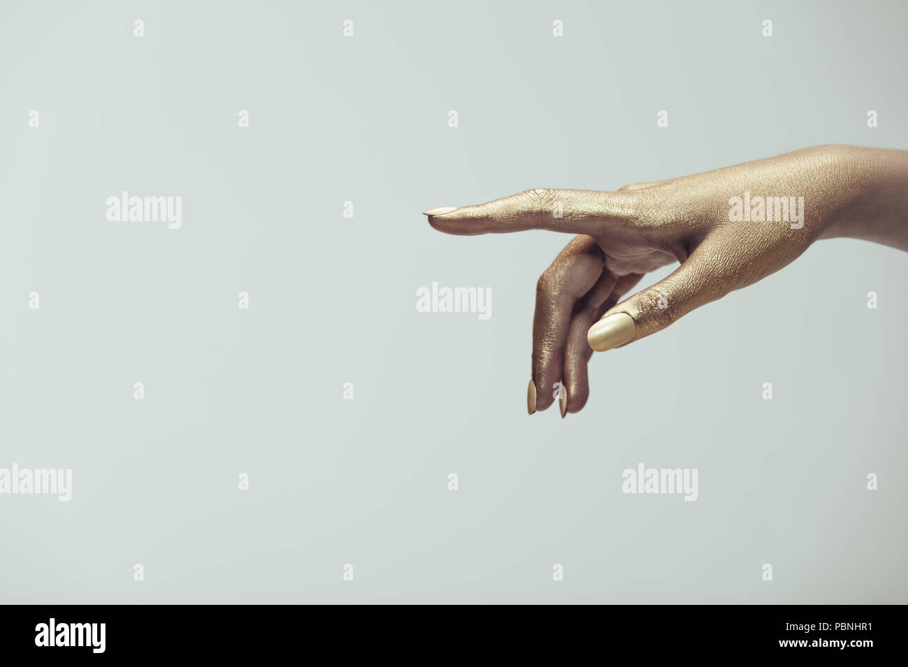 Golden painted hand pointing over grey background. Female hand in ...