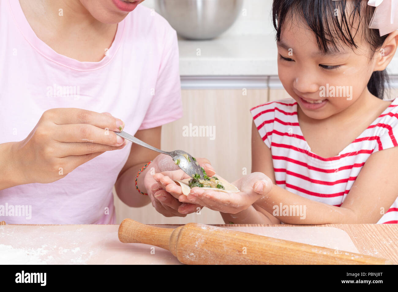 Asian Chinese mother and daughter making dumpling in the kitchen at ...