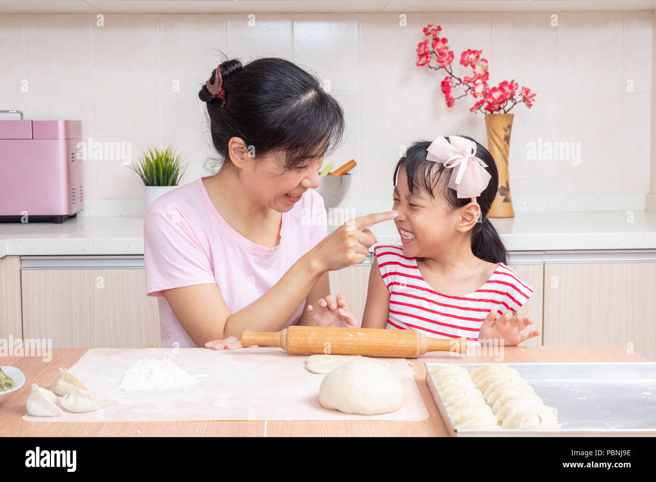 Asian Chinese mother and daughter making dumpling in the kitchen at ...