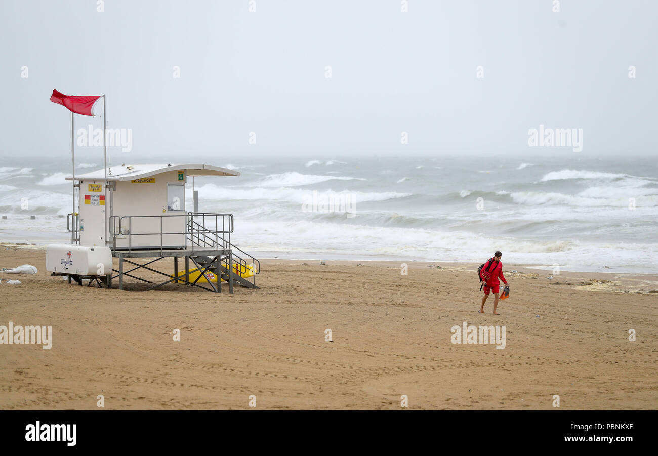 A lifeguard makes his way along Bournemouth beach in Dorset, as heavy ...