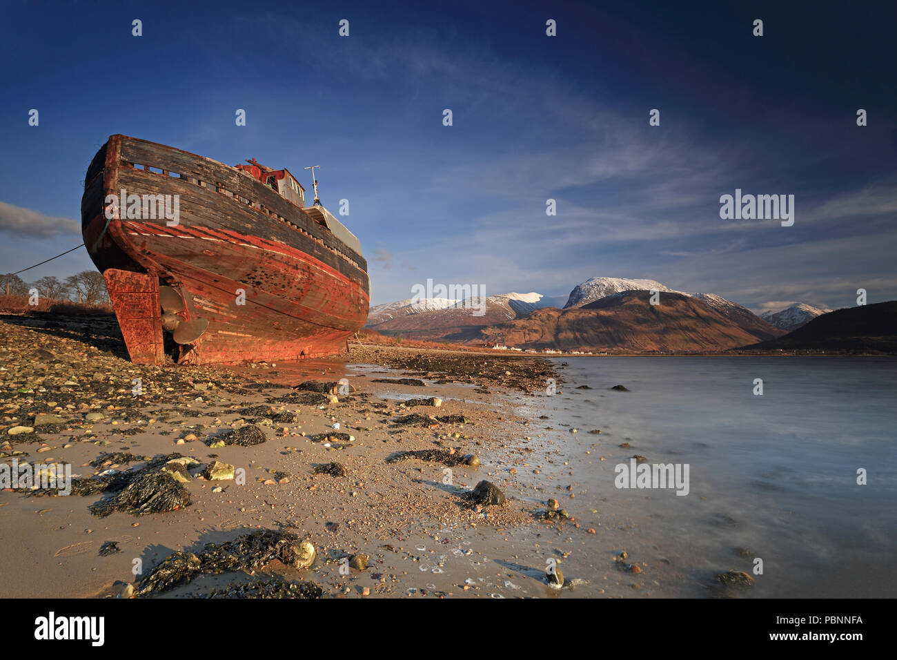 An old rusty abandoned boat facing a snow-capped Ben Nevis and the ...
