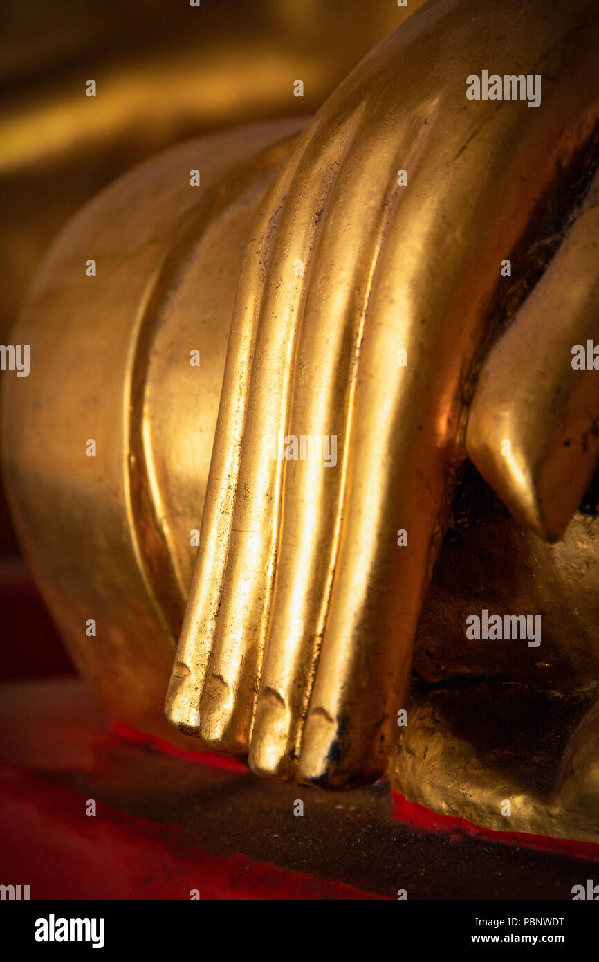 Vertical scene of close focus on fingers and hand of golden Buddha ...