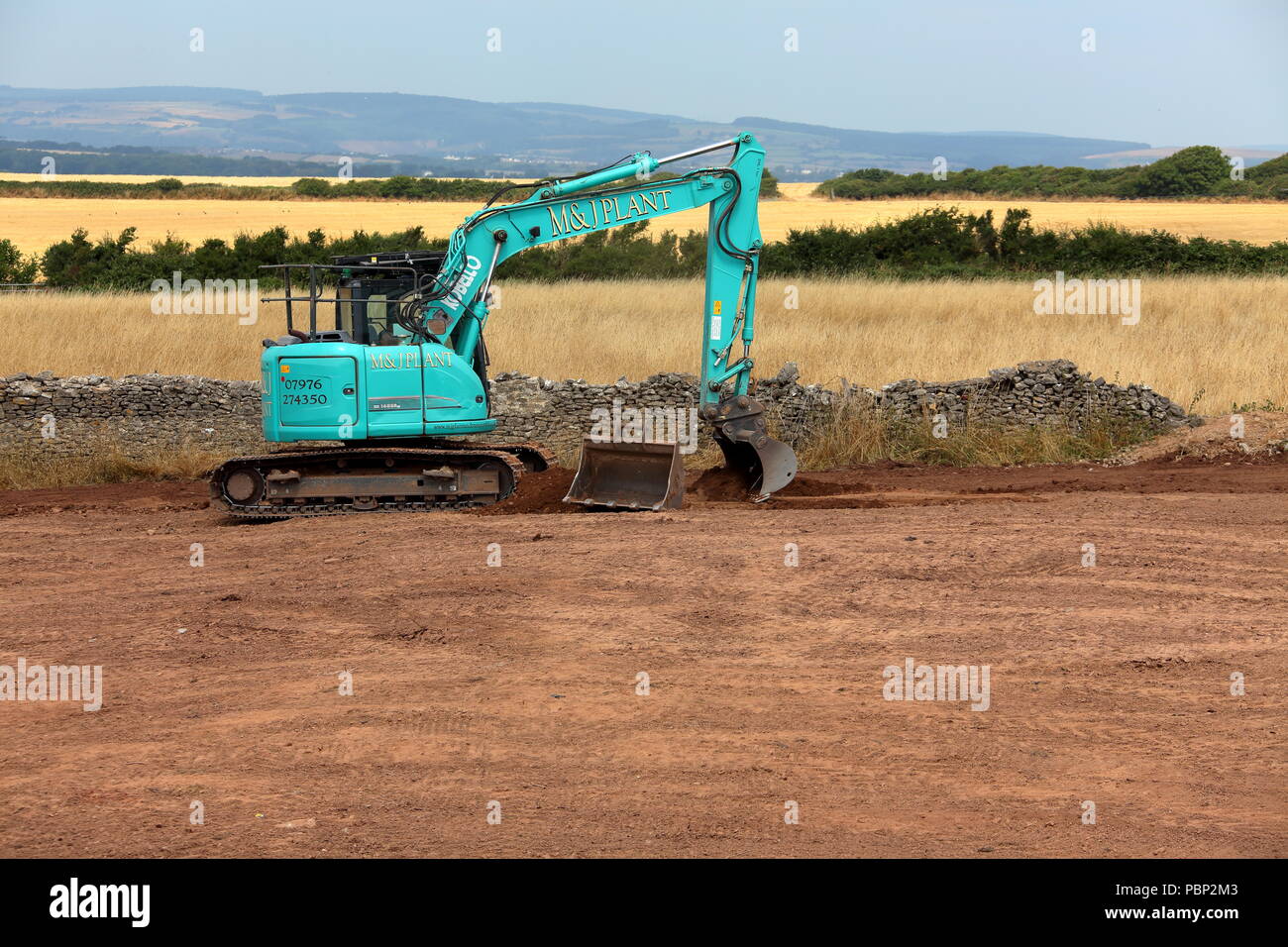 A newly commisioned large tracked digger levelling off the earth in a ...