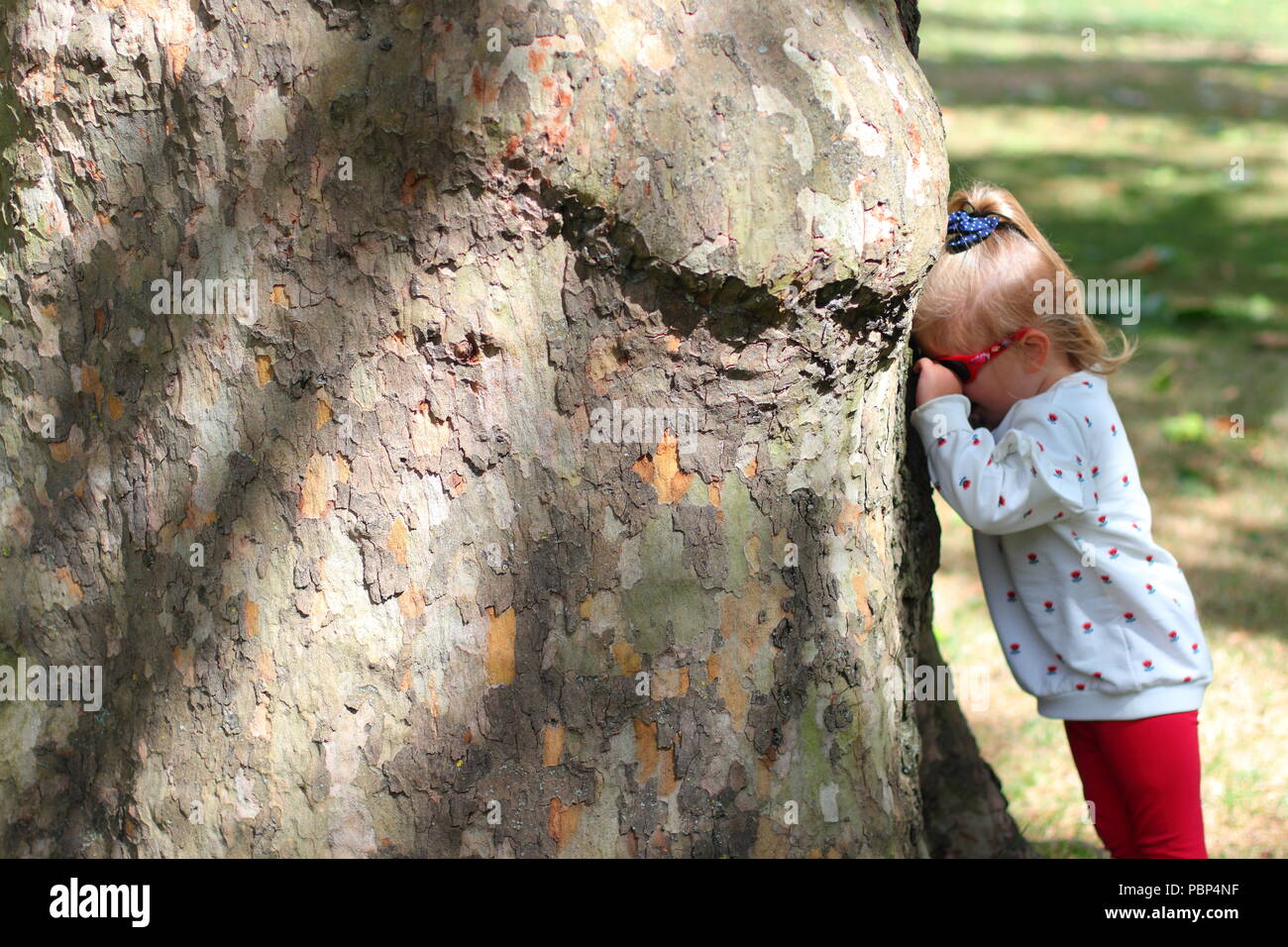 concept of crying, sulking or playing hide and seek by a young girl ...