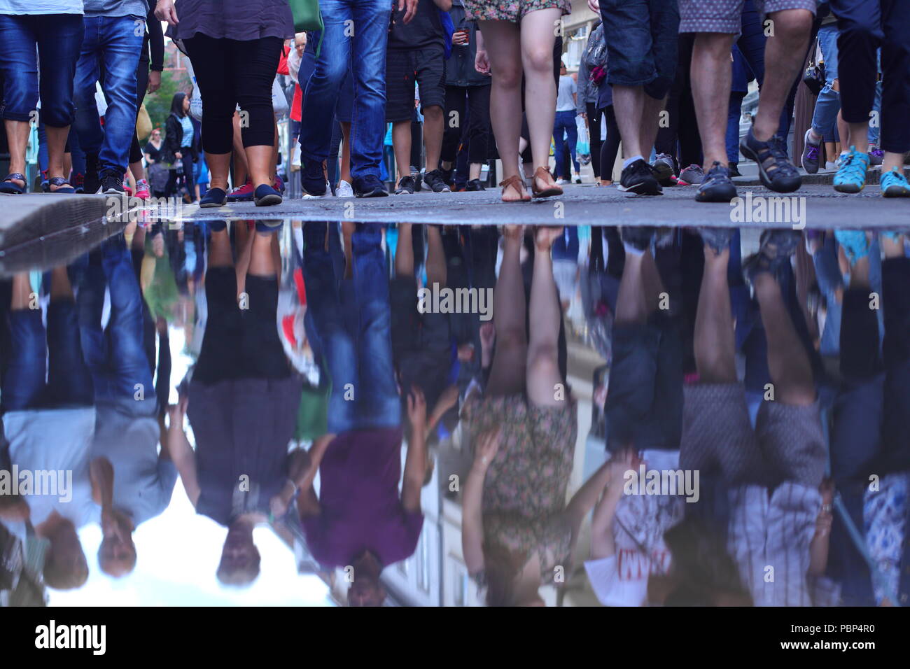 Reflections from a puddle of visitors to the City of York , UK Stock ...