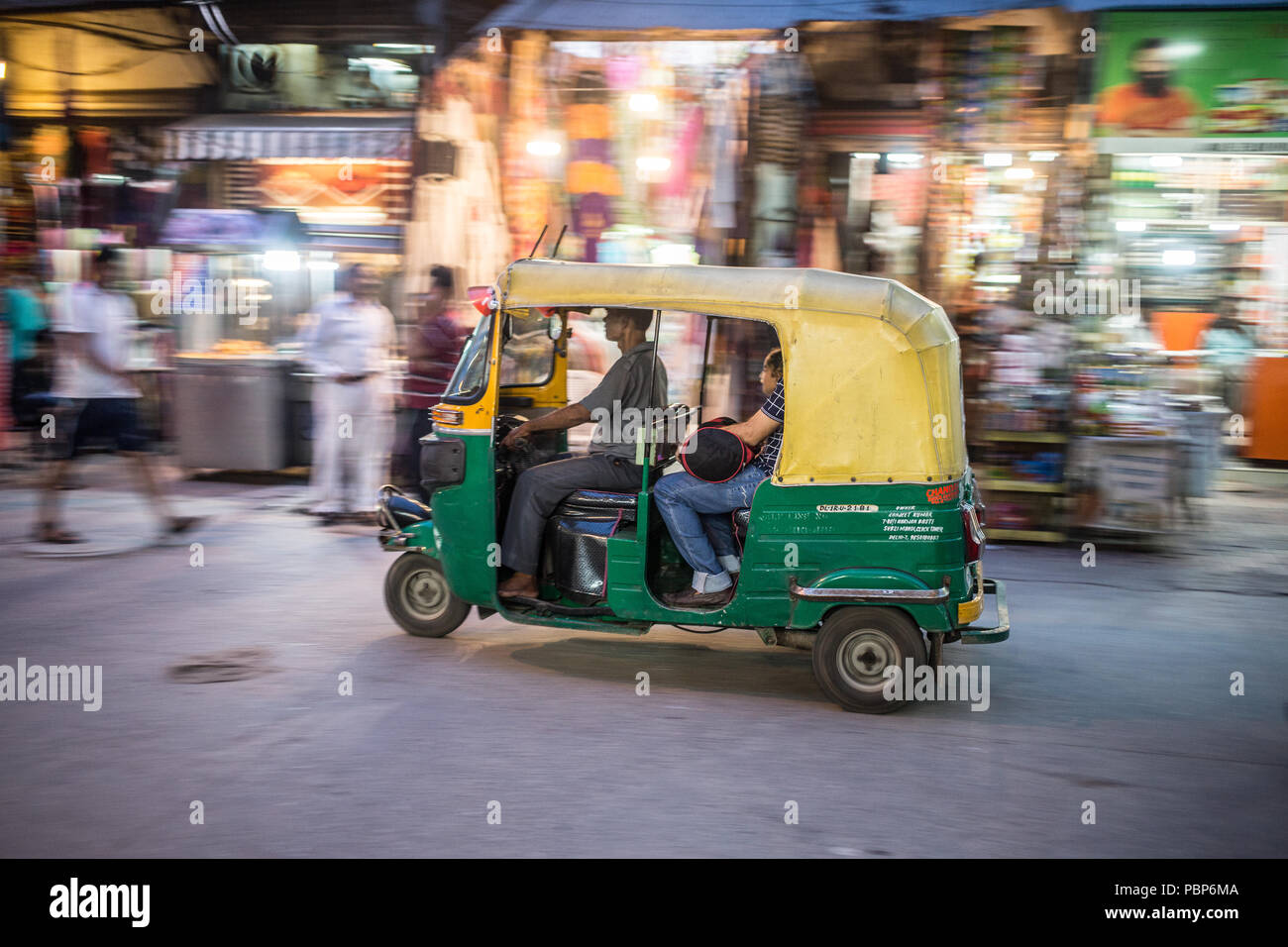 A auto rickshaw driving through a street in the evening in New Delhi ...