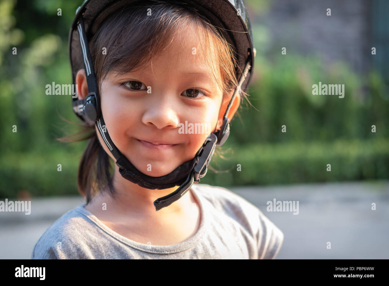 a smiling girl putting on kid helmet Stock Photo - Alamy