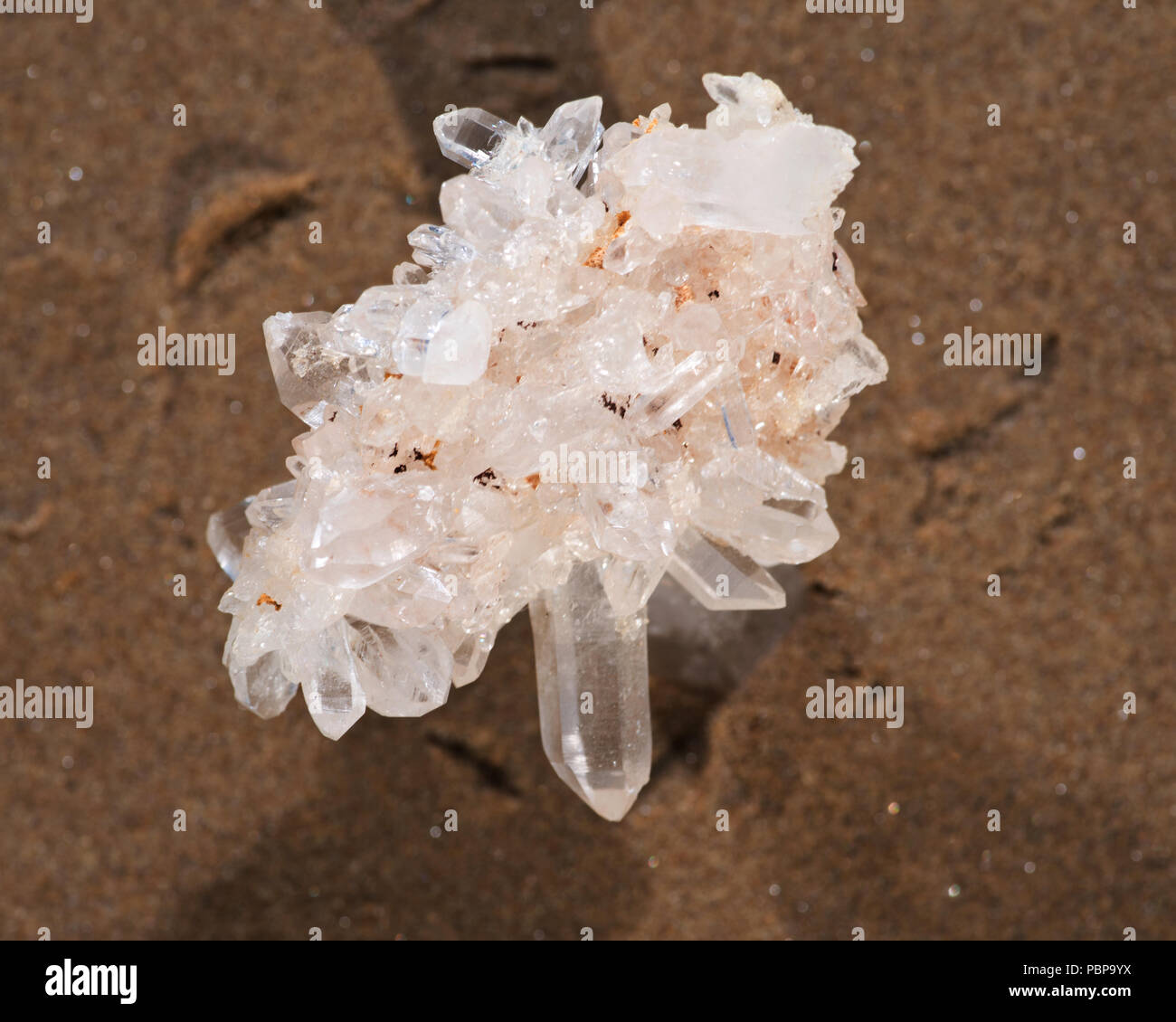 Himalayan clear quartz cluster with hematite inclusions on wet sand on ...