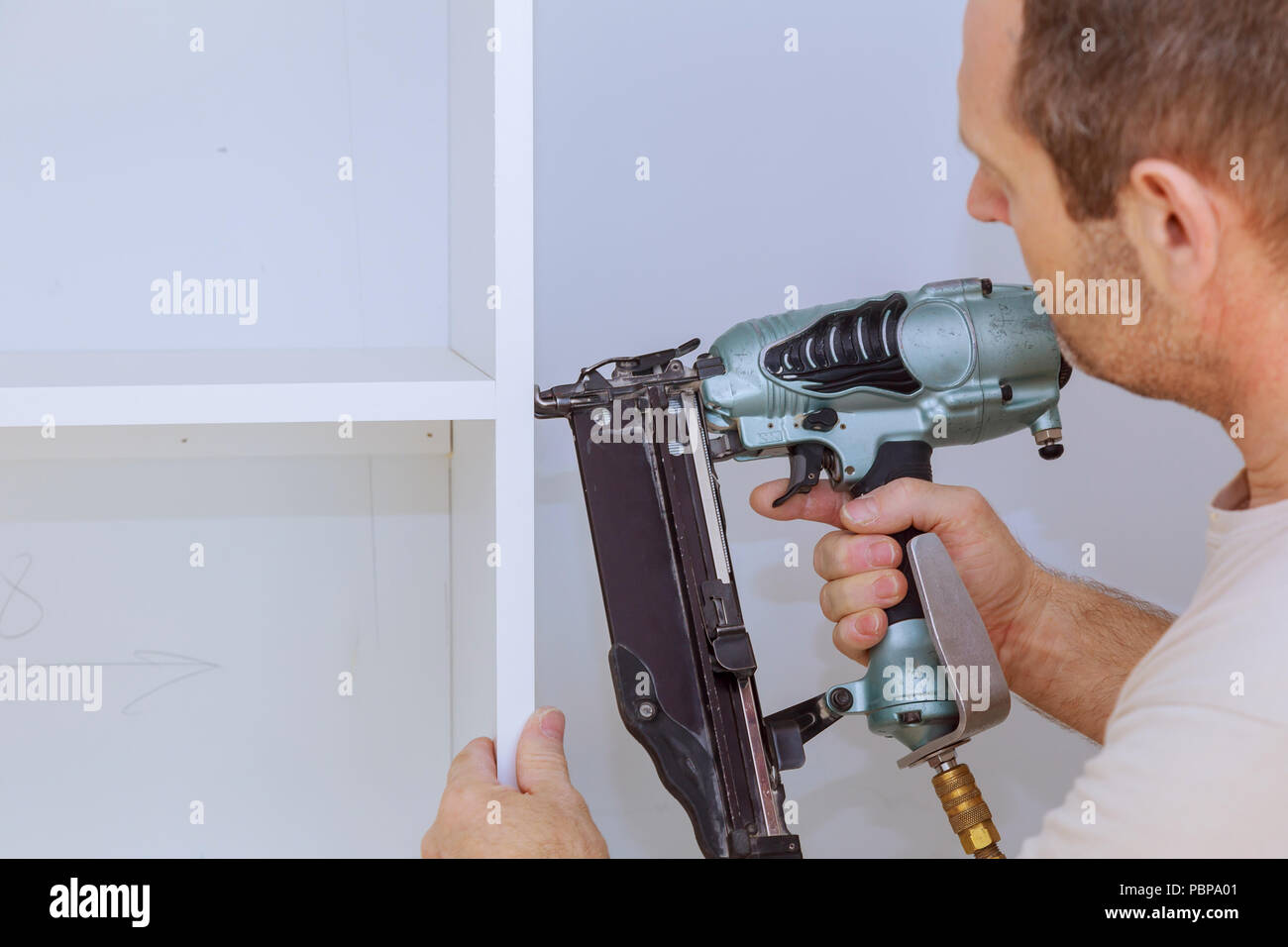 Profile view of a good looking young handyman making some air gun holes ...