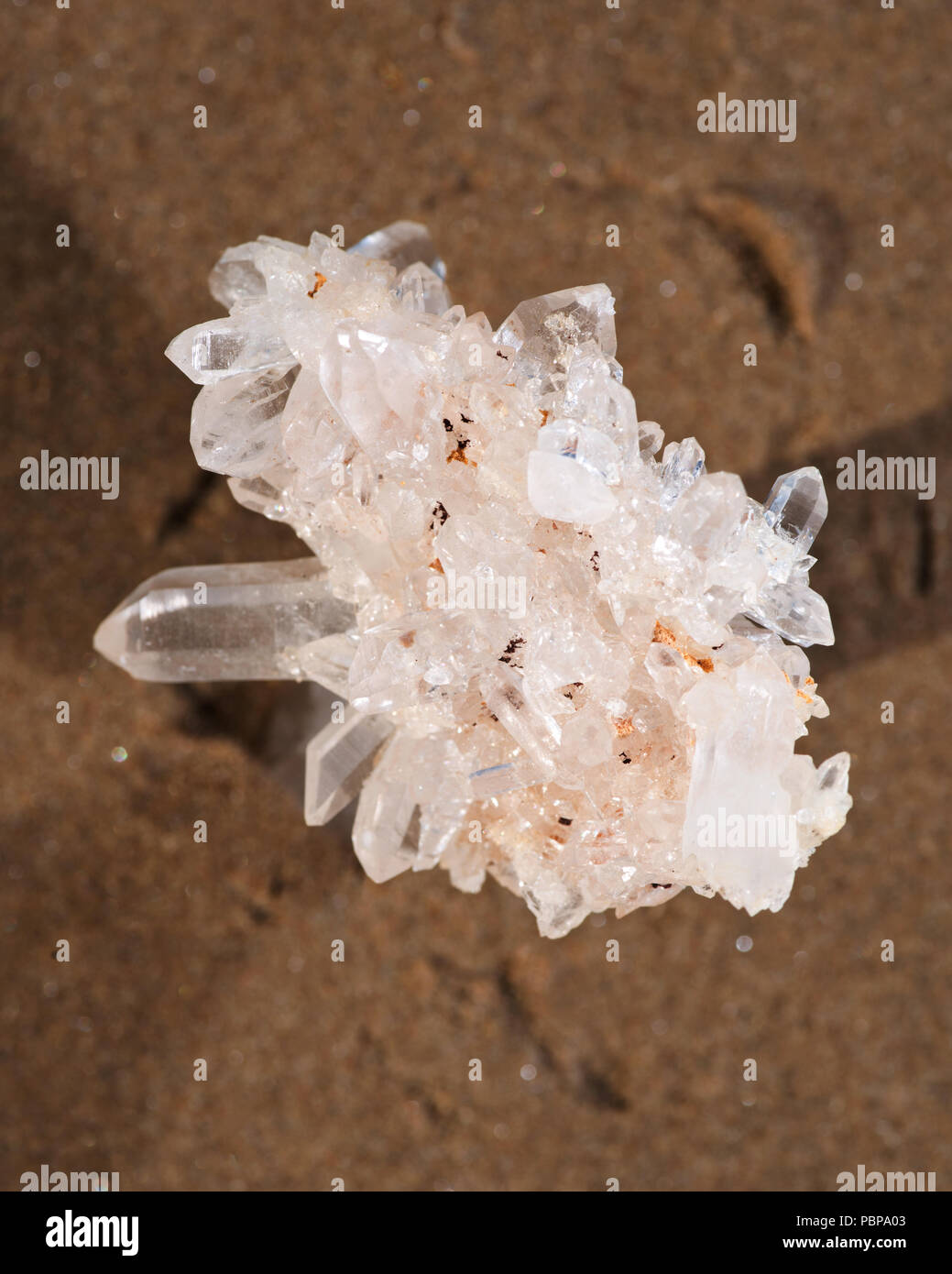 Himalayan clear quartz cluster with hematite inclusions on wet sand on ...