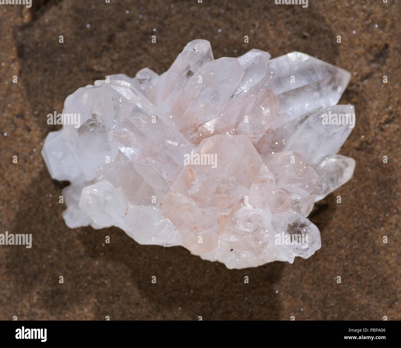 Himalayan clear quartz cluster with hematite inclusions on wet sand on ...