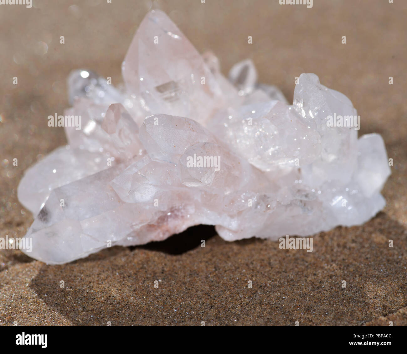 Himalayan clear quartz cluster with hematite inclusions on wet sand on ...