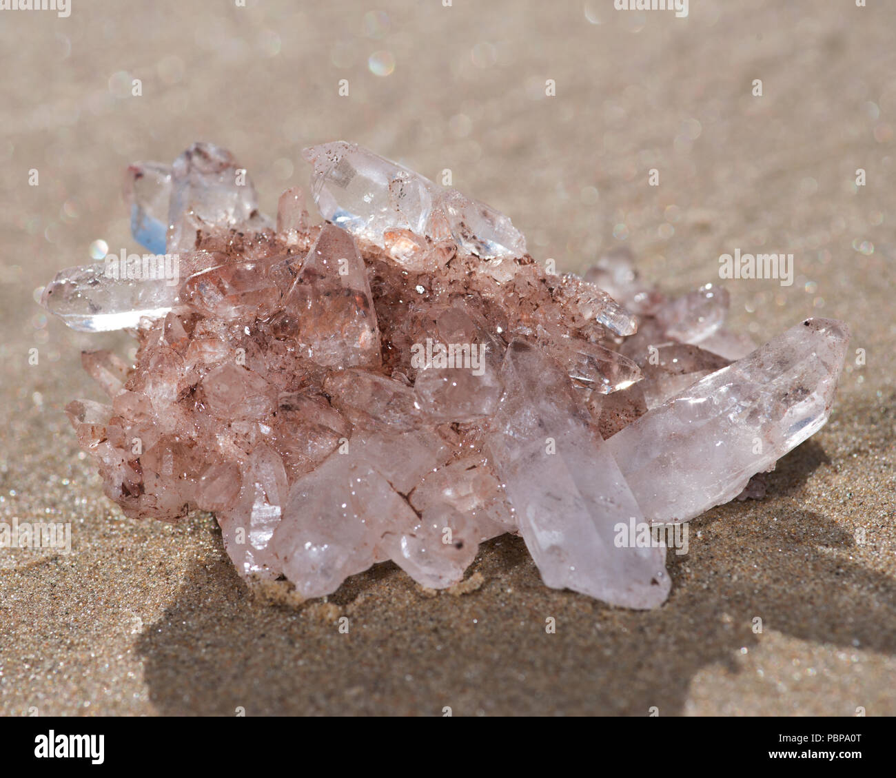 Himalayan clear quartz cluster with hematite inclusions on wet sand on ...