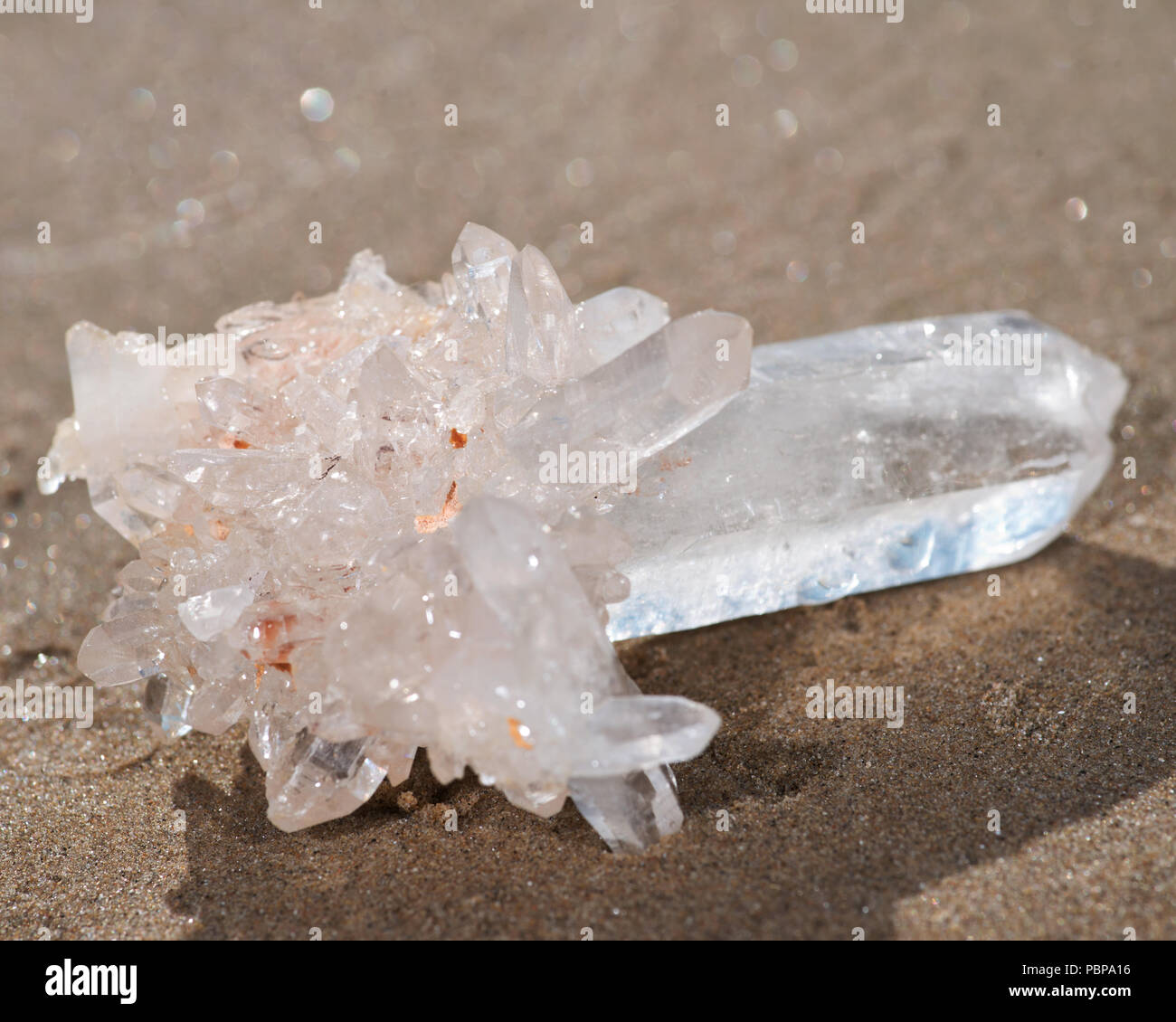 Himalayan clear quartz cluster with hematite inclusions on wet sand on ...
