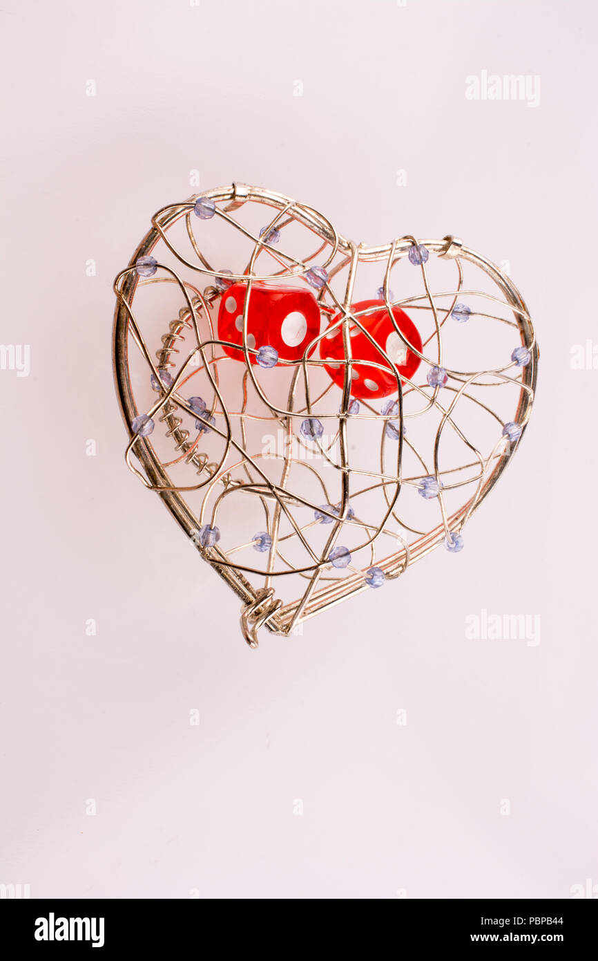 Red dice in a heart shaped cage on a white background Stock Photo - Alamy