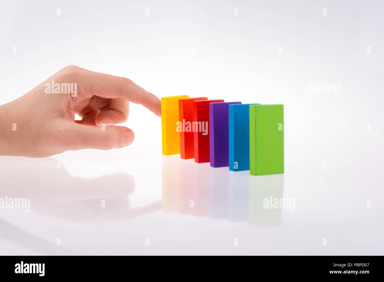 Hand playing with colored domino on white background Stock Photo - Alamy