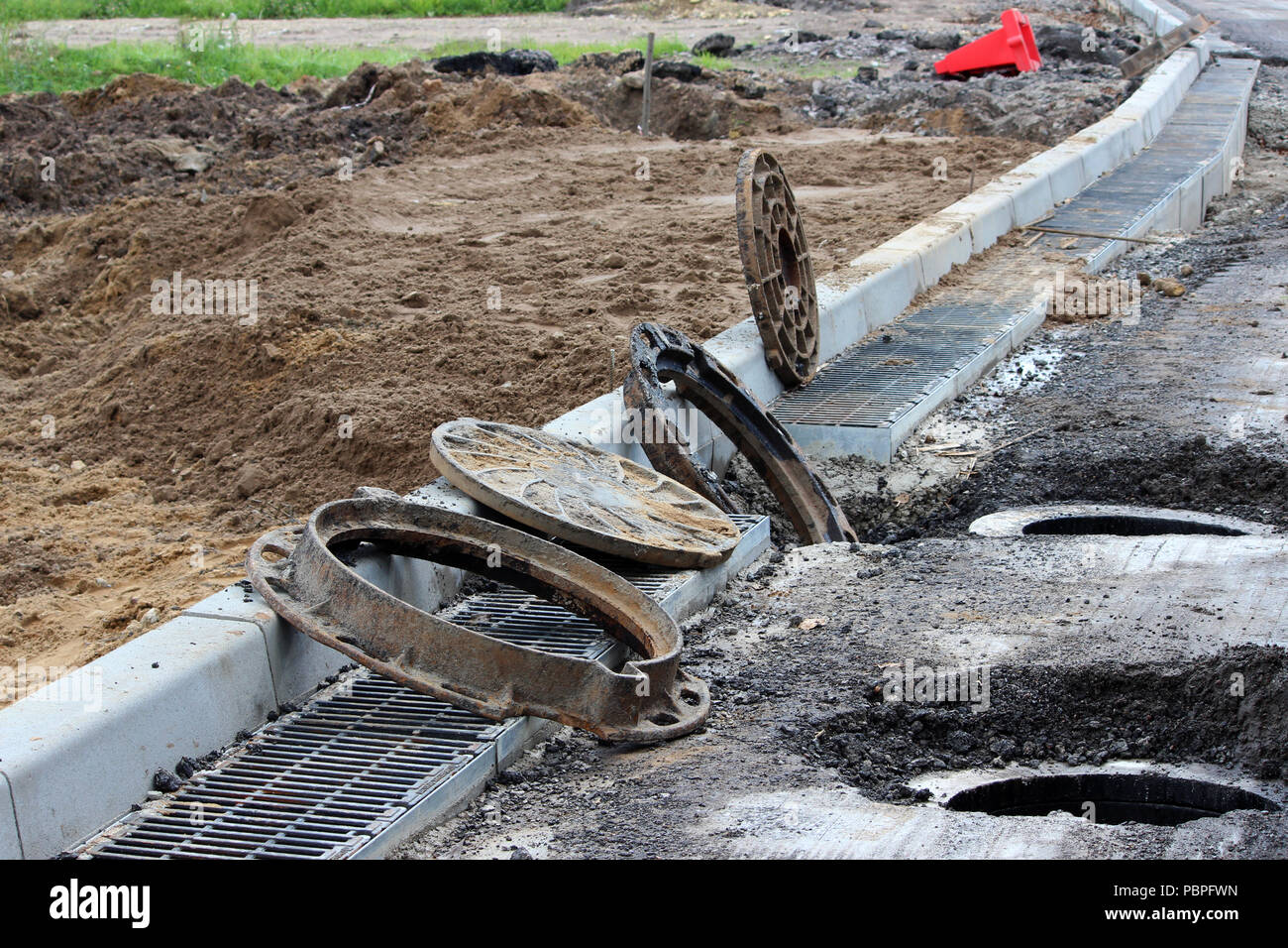 many rusty round hatches and a rainwater grid on the side of the city ...