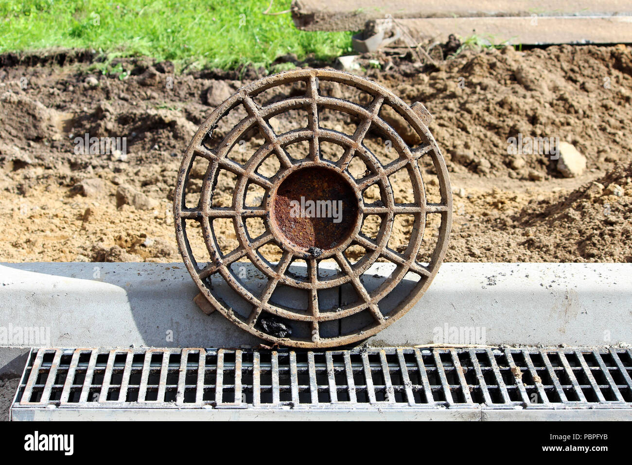 rusty round hatch and grate for rainwater on the side of the city road ...