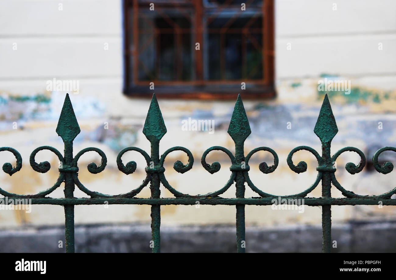 The old metal city fence with sharp points is painted on top with green ...