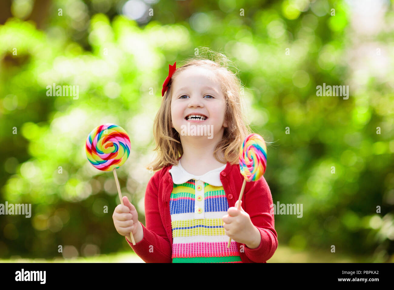 Cute little girl with big colorful lollipop. Child eating sweet candy ...