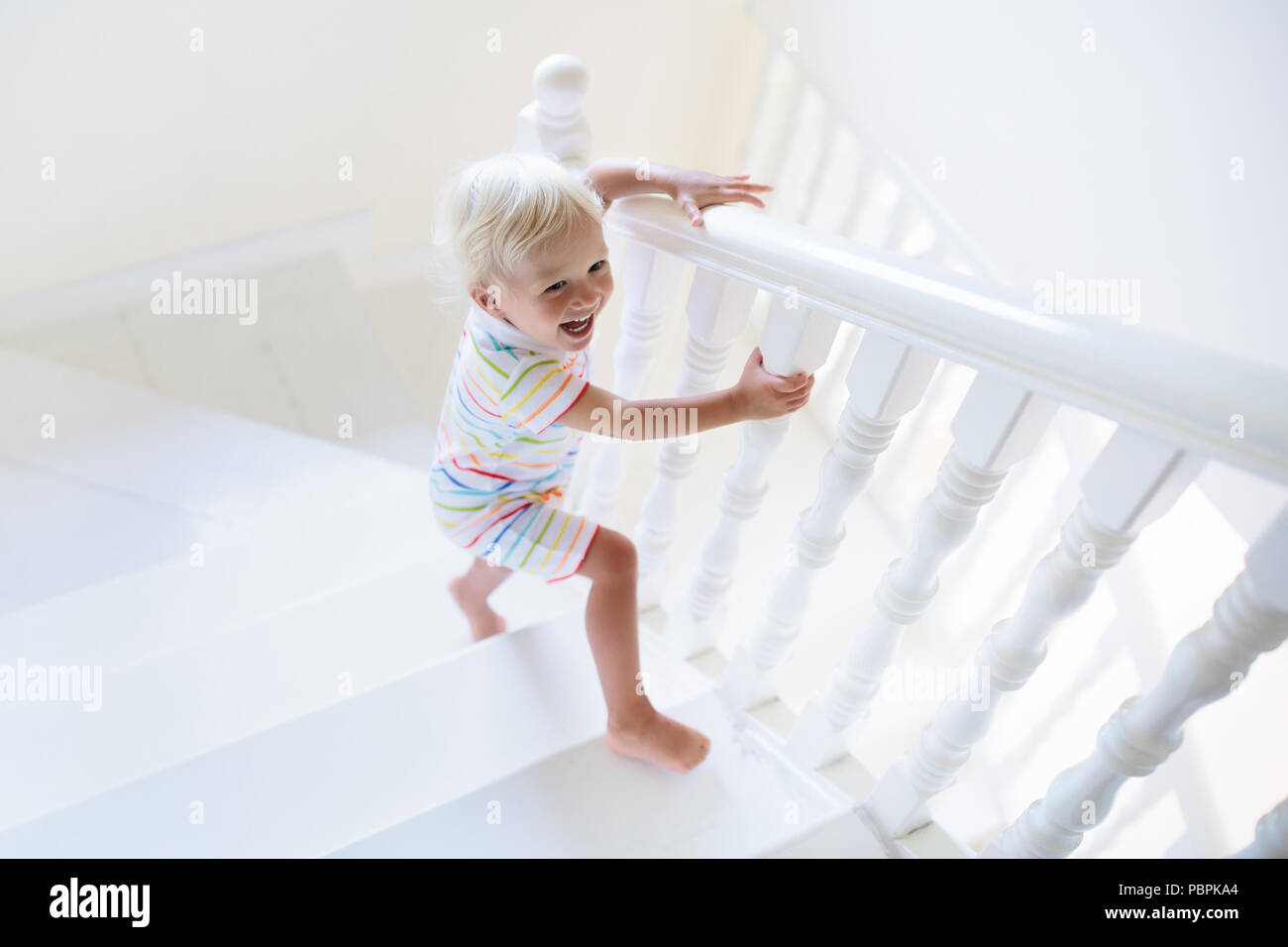 Kid walking stairs in white house. Baby boy playing in sunny staircase ...
