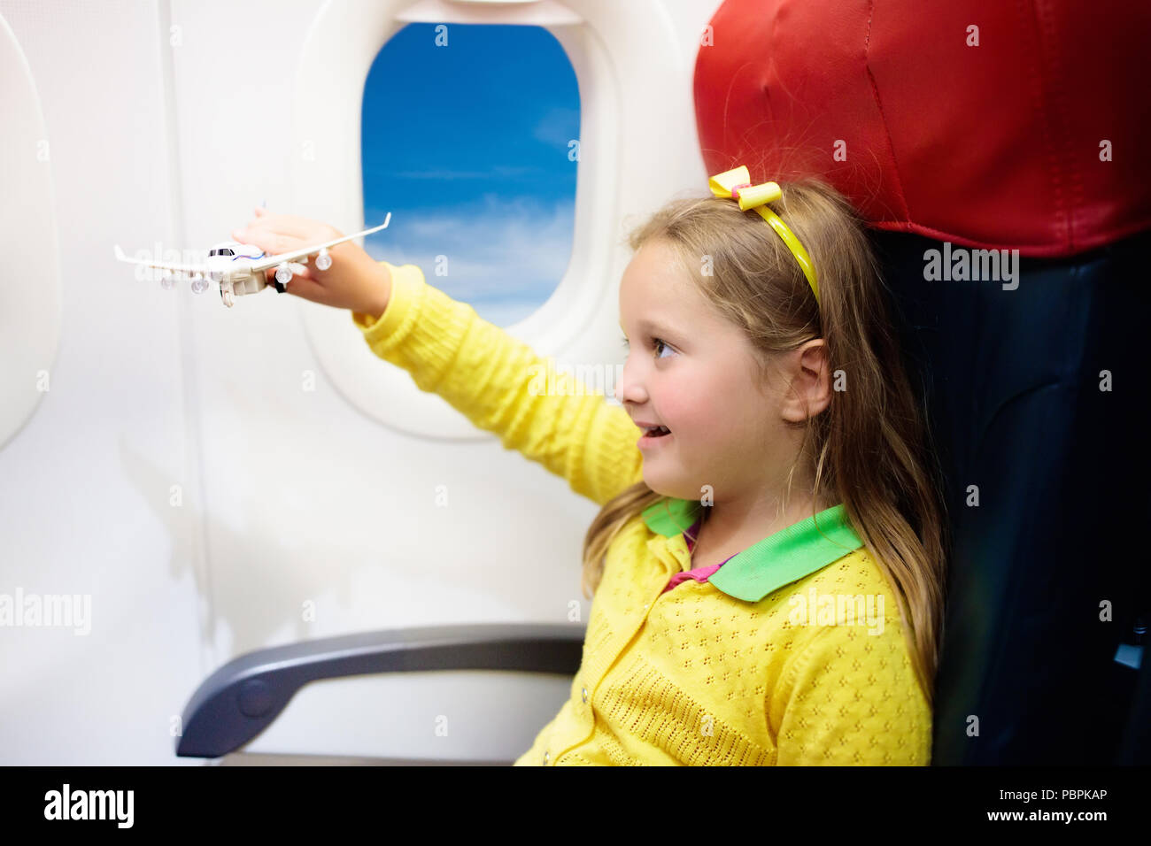 Child in airplane. Kid in air plane sitting in window seat. Flight ...