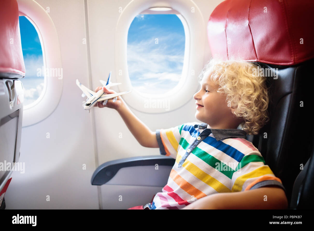 Child in airplane. Kid in air plane sitting in window seat. Flight ...