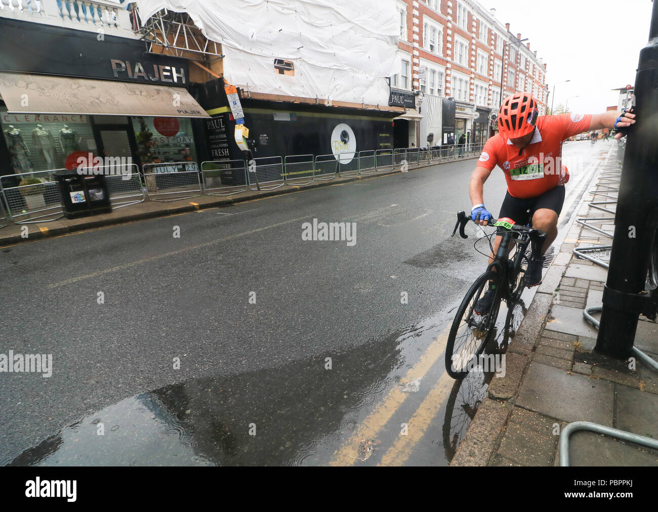 London UK. 29th July 2018. Cyclists pass through Wimbledon village in ...