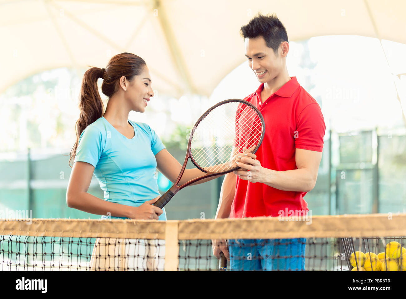 Tennis instructor teaching a beginner player the correct grip Stock ...