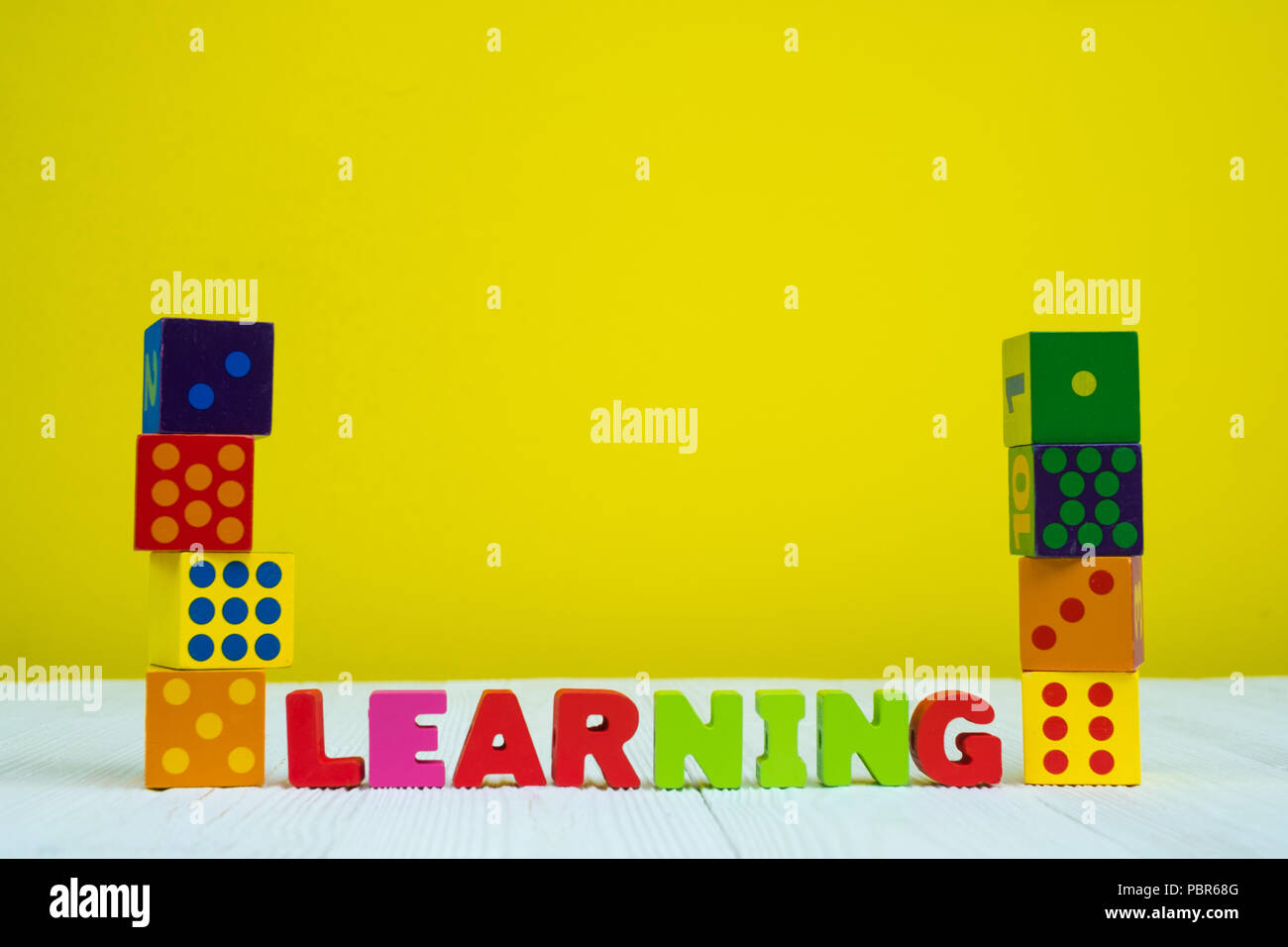 LEARNING text alphabet and toy square block puzzle on table with yellow ...