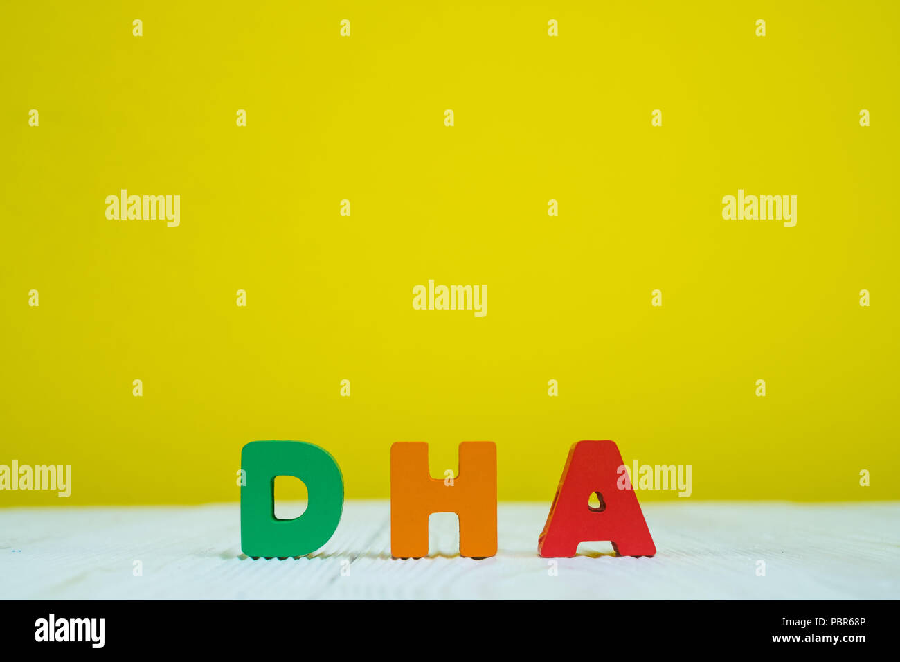 DHA text alphabet on white wooden table. yellow wall background with ...