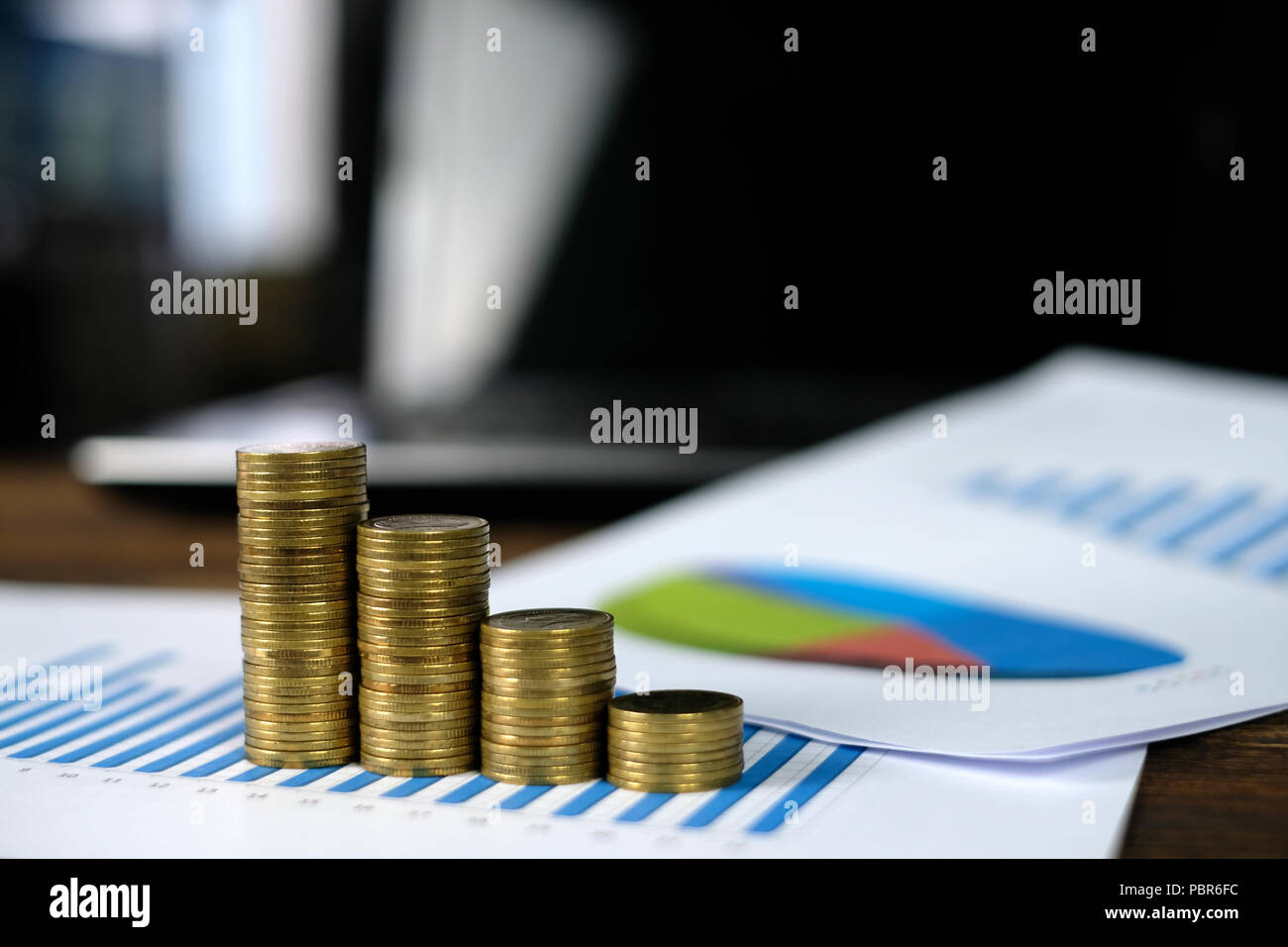 Step of coins stacks with notebook laptop computer and financial graph ...