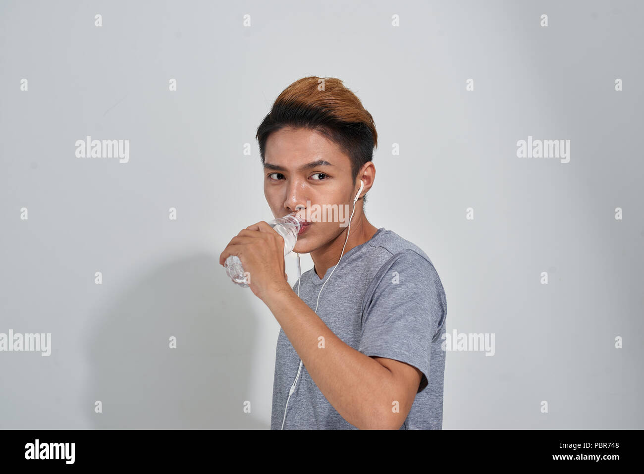 Handsome young muscular sportsman holding a bottle of water and ...