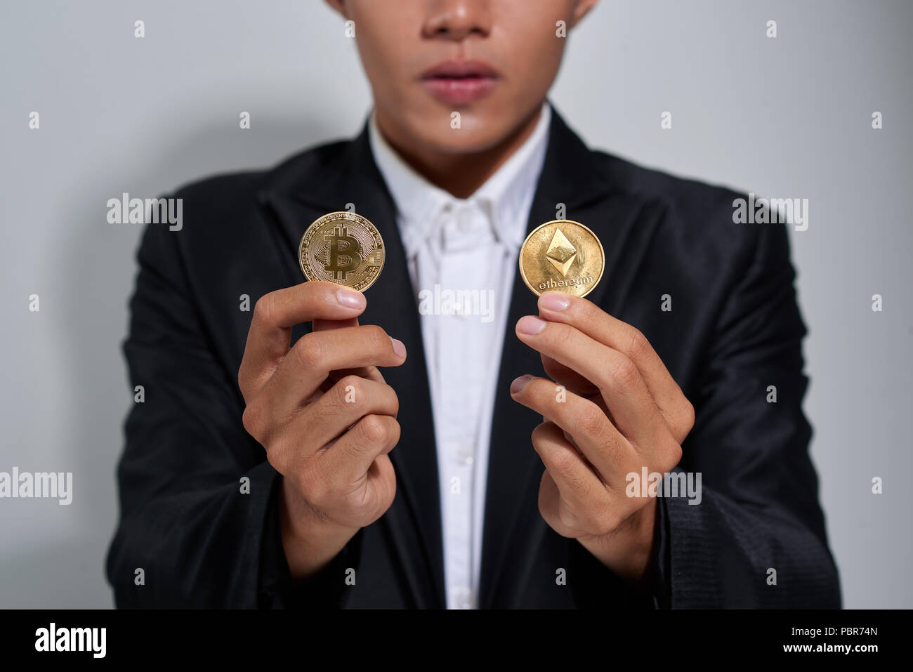 A smiling young man dressed in shirt and jacket showing two golden ...