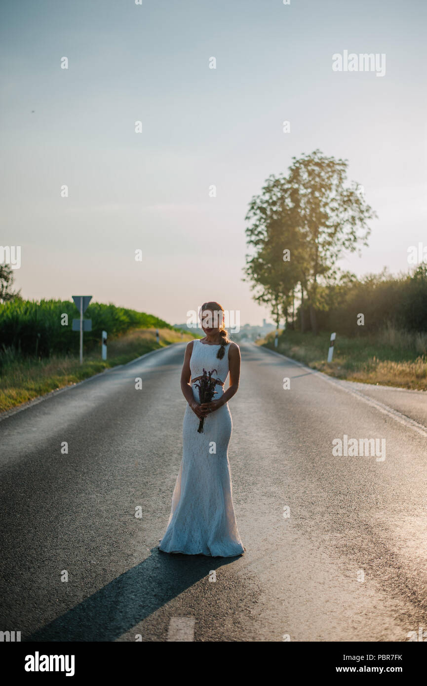 Bride standing in the middle of the road under the sunset light Stock ...