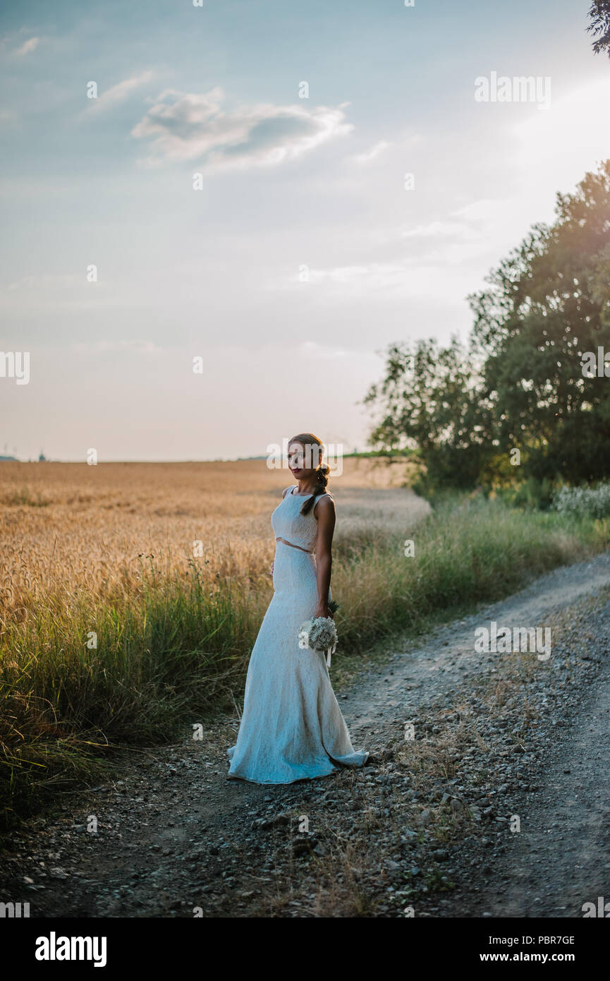 Bride shooting with a bouquet in a field Stock Photo - Alamy